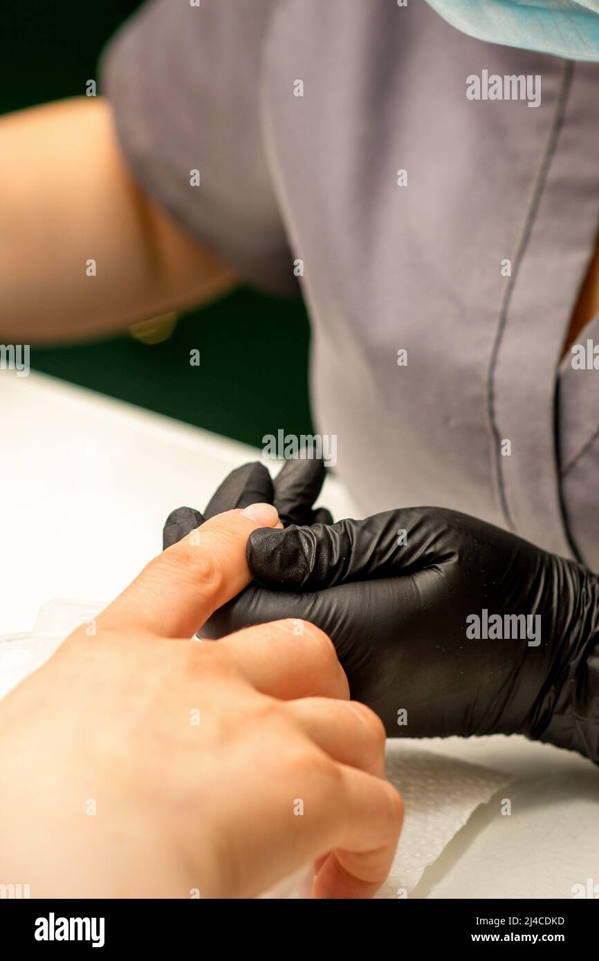 Close up professional manicure master holds the female hand of the ...