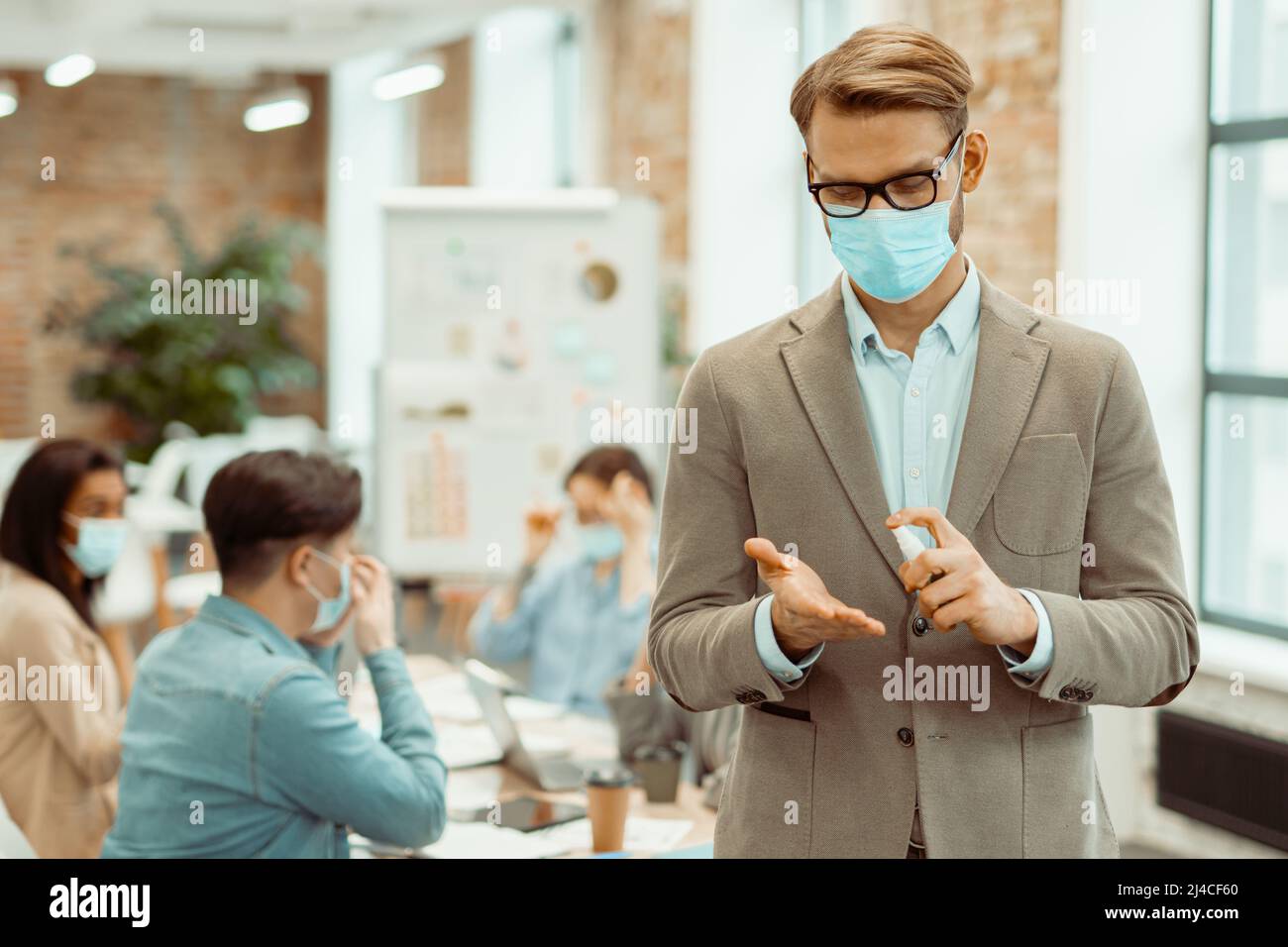 Male employee sanitizing hands in the office Stock Photo - Alamy