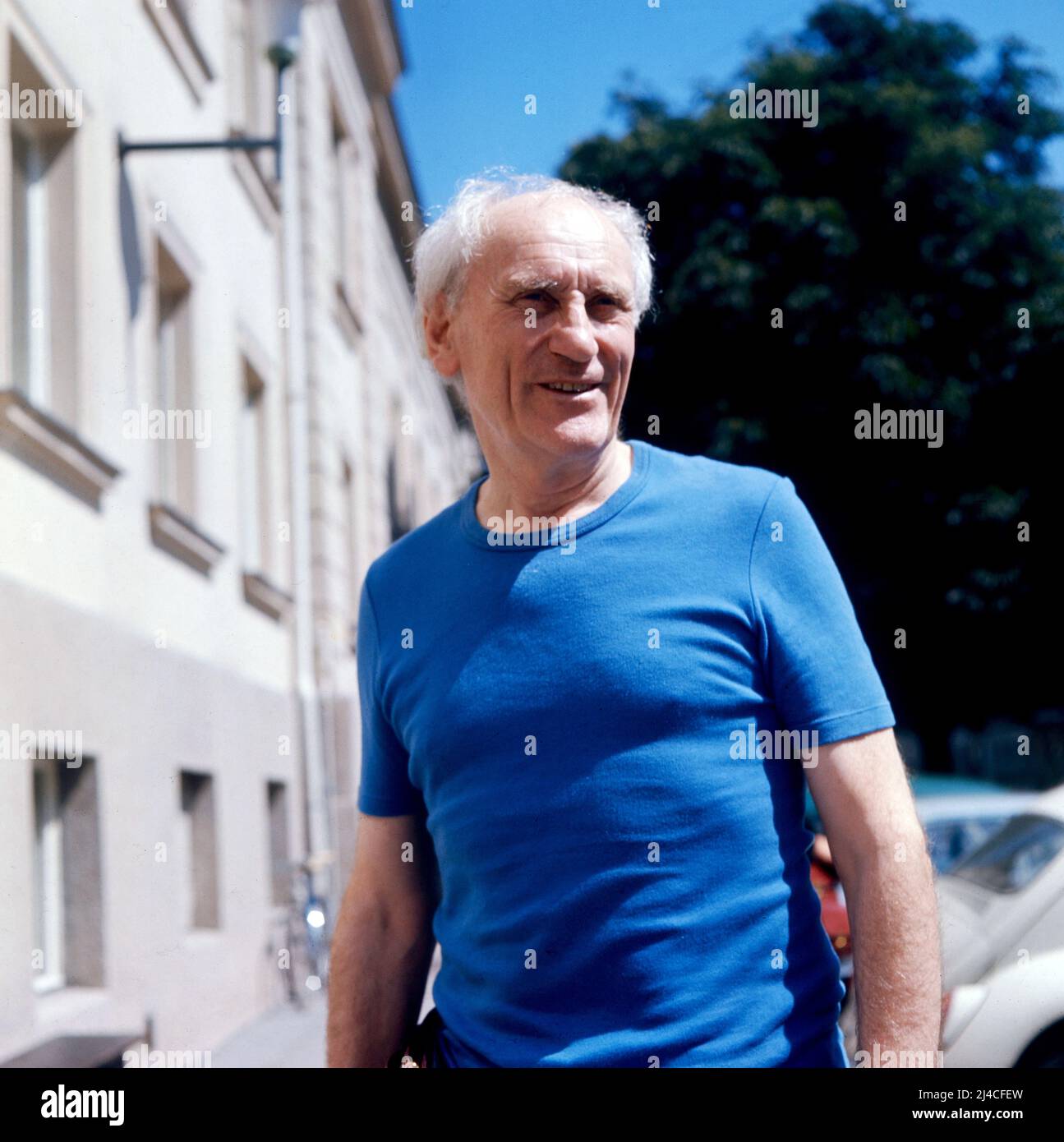 Bernhard Minetti, deutscher Schauspieler, zwischen parkenden Autos auf ...