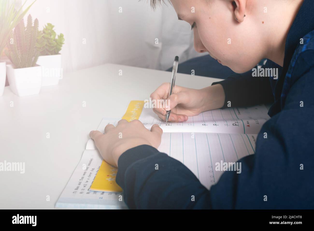 Teenager doing homework sitting at white desk Stock Photo - Alamy