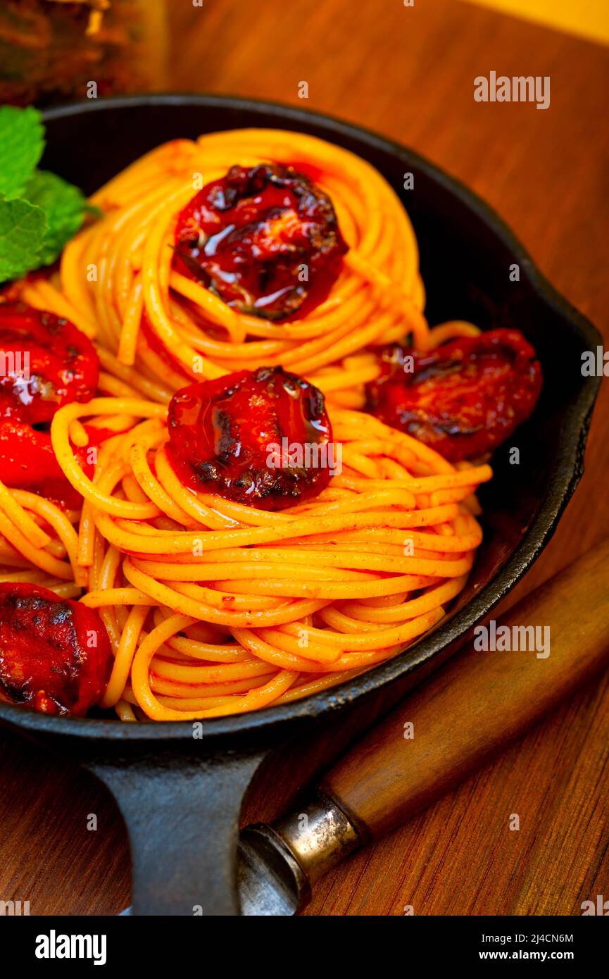 Italian spaghetti pasta and tomato with mint leaves on iron skillet ...