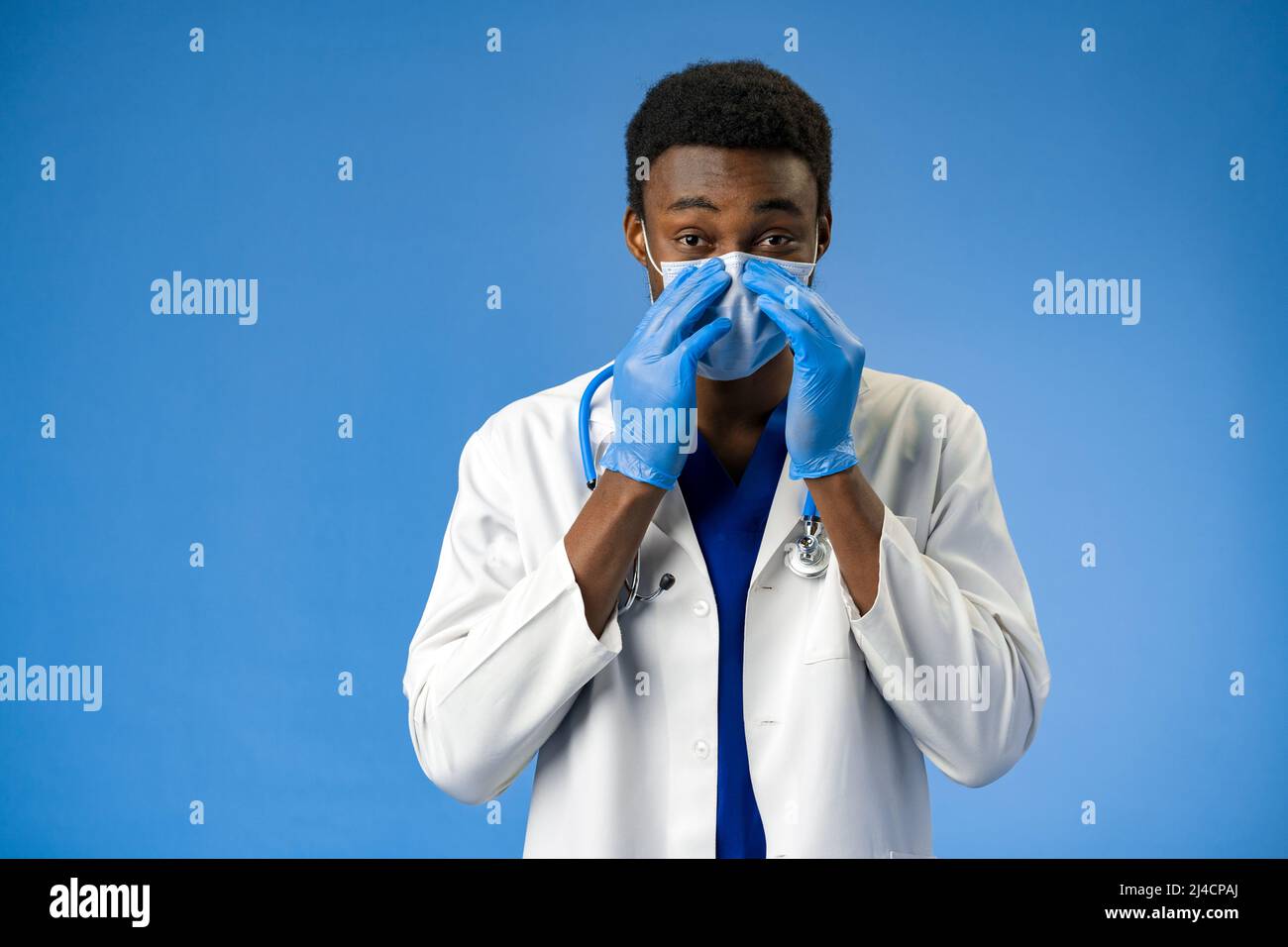 Confident black doctor in face mask and gloves in blue studio Stock ...