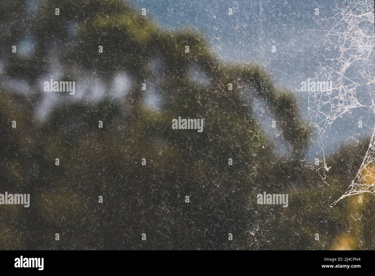 dirty winow with spider webs and dark moody weather over mysterious ...