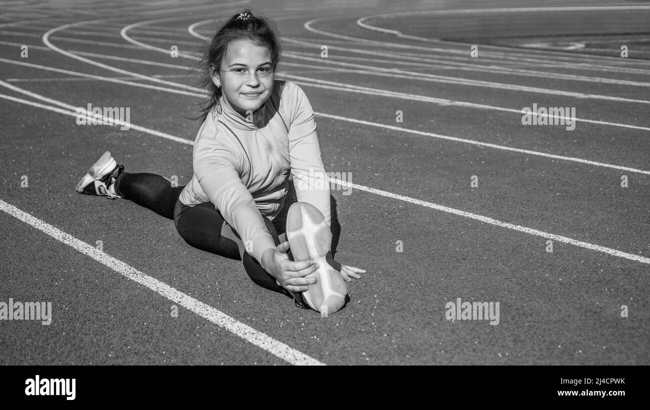 girl kid training sport outside on stadium arena sit in split ...