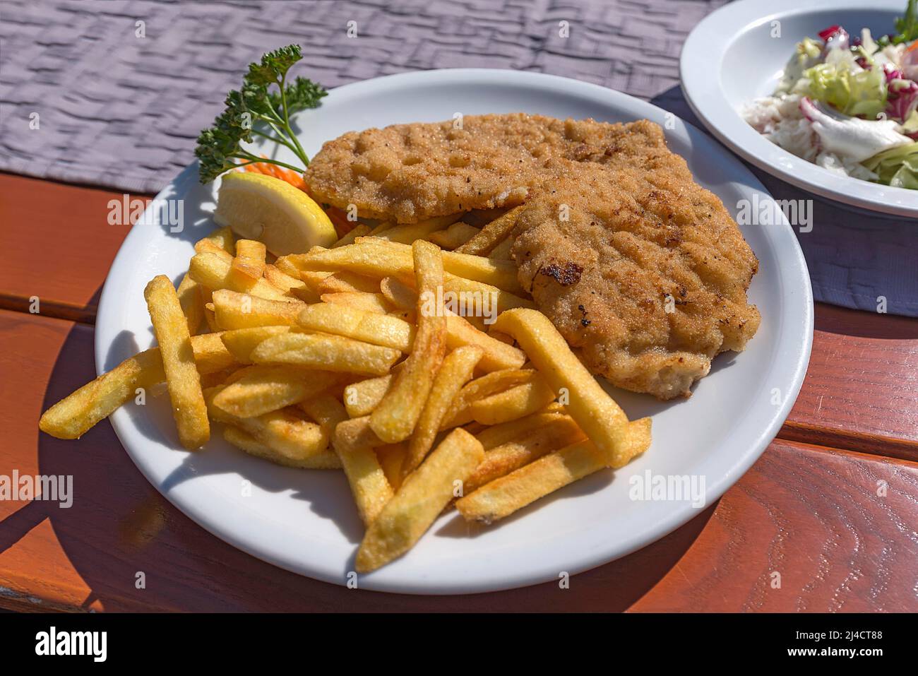 Wiener schnitzel served with french fries in a garden restaurant ...
