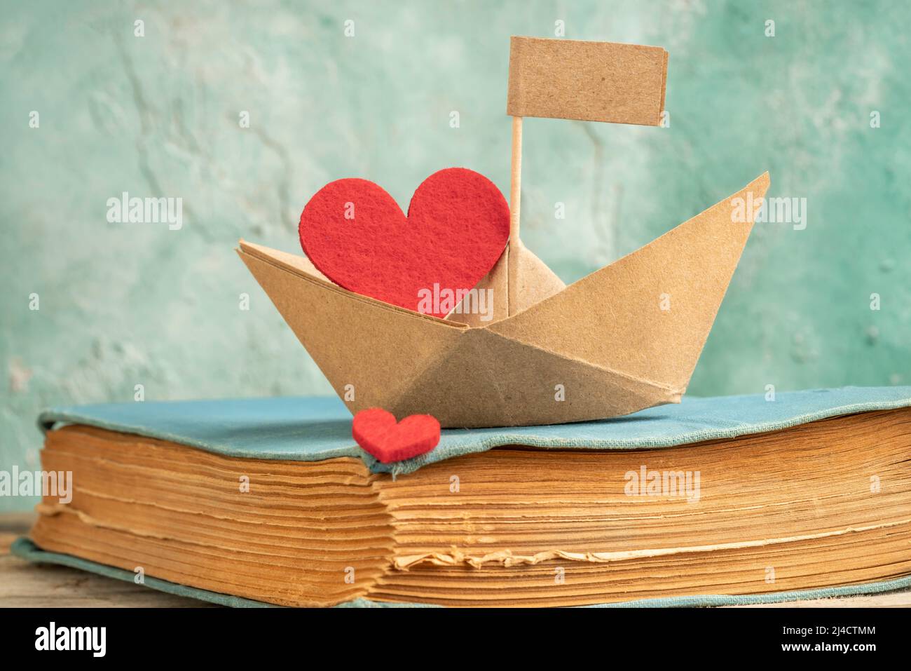 origami paper boat on an old book on table isolated green background or ...