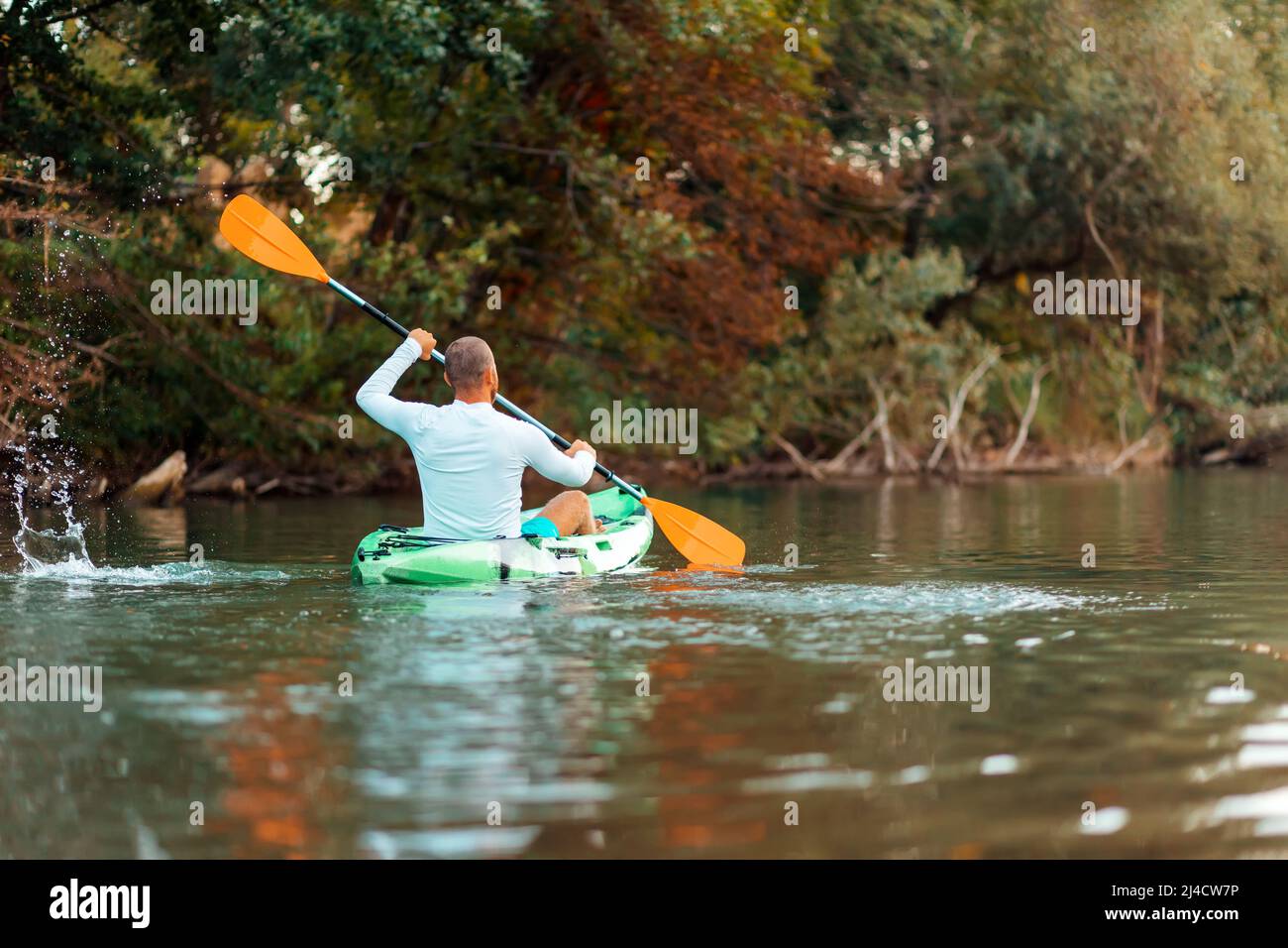 Kayaking on the river. Adult man floating at the kayak. Back view. Copy ...