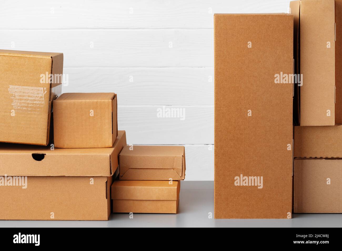 Group of cardboard boxes against white wooden wall Stock Photo - Alamy