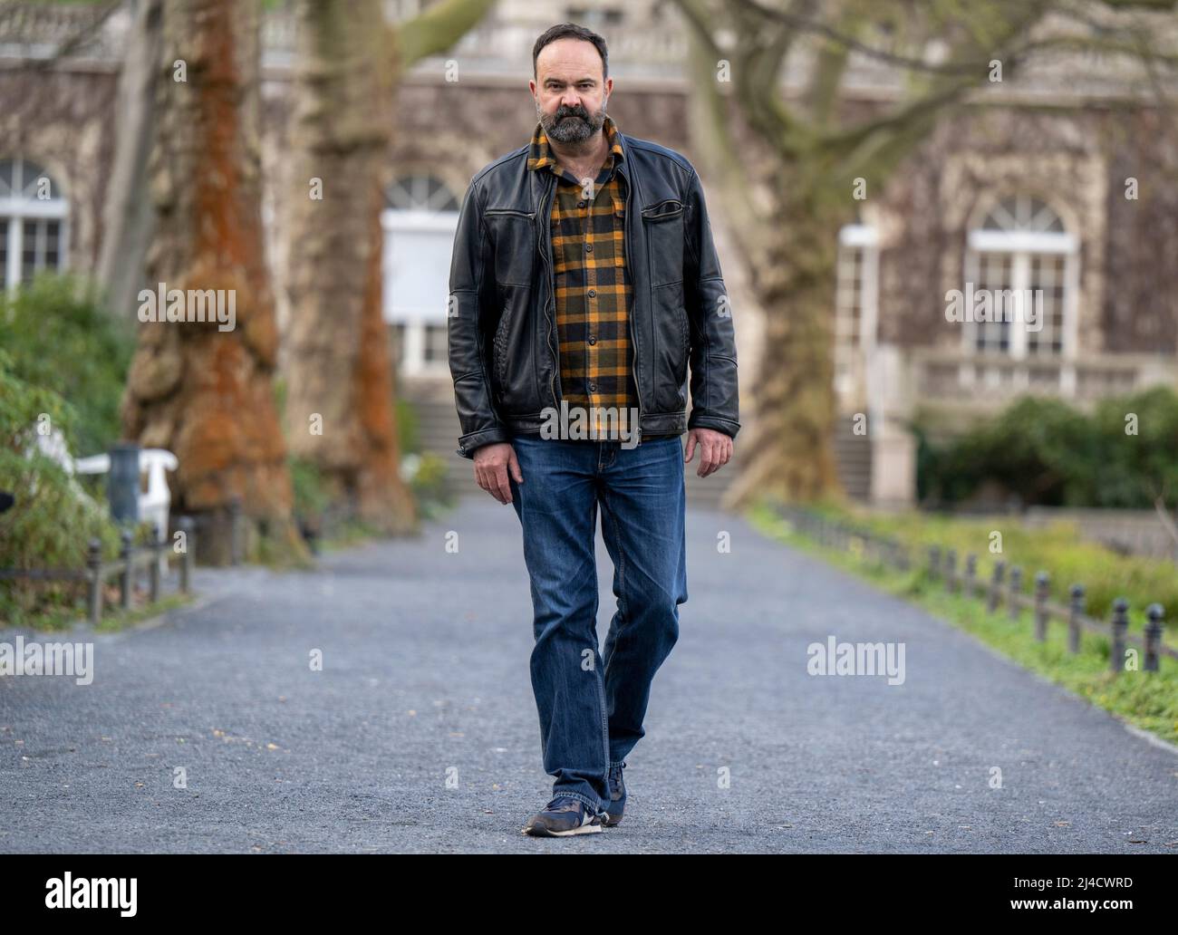 Berlin, Germany. 11th Apr, 2022. Actor Tom Keune sits across a park ...
