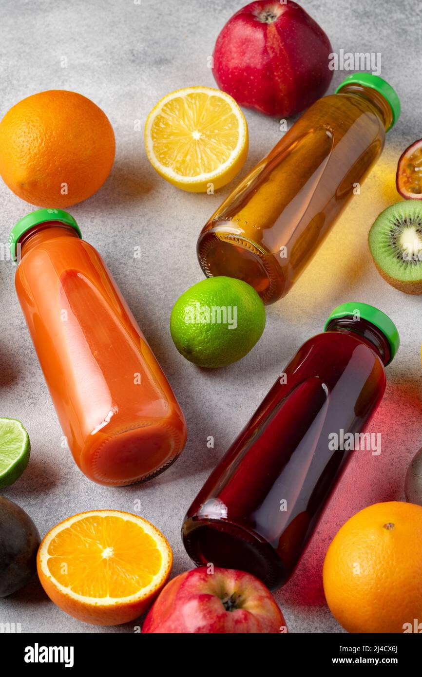 Various fruits and freshly squeezed fruits juice in bottle on gray ...