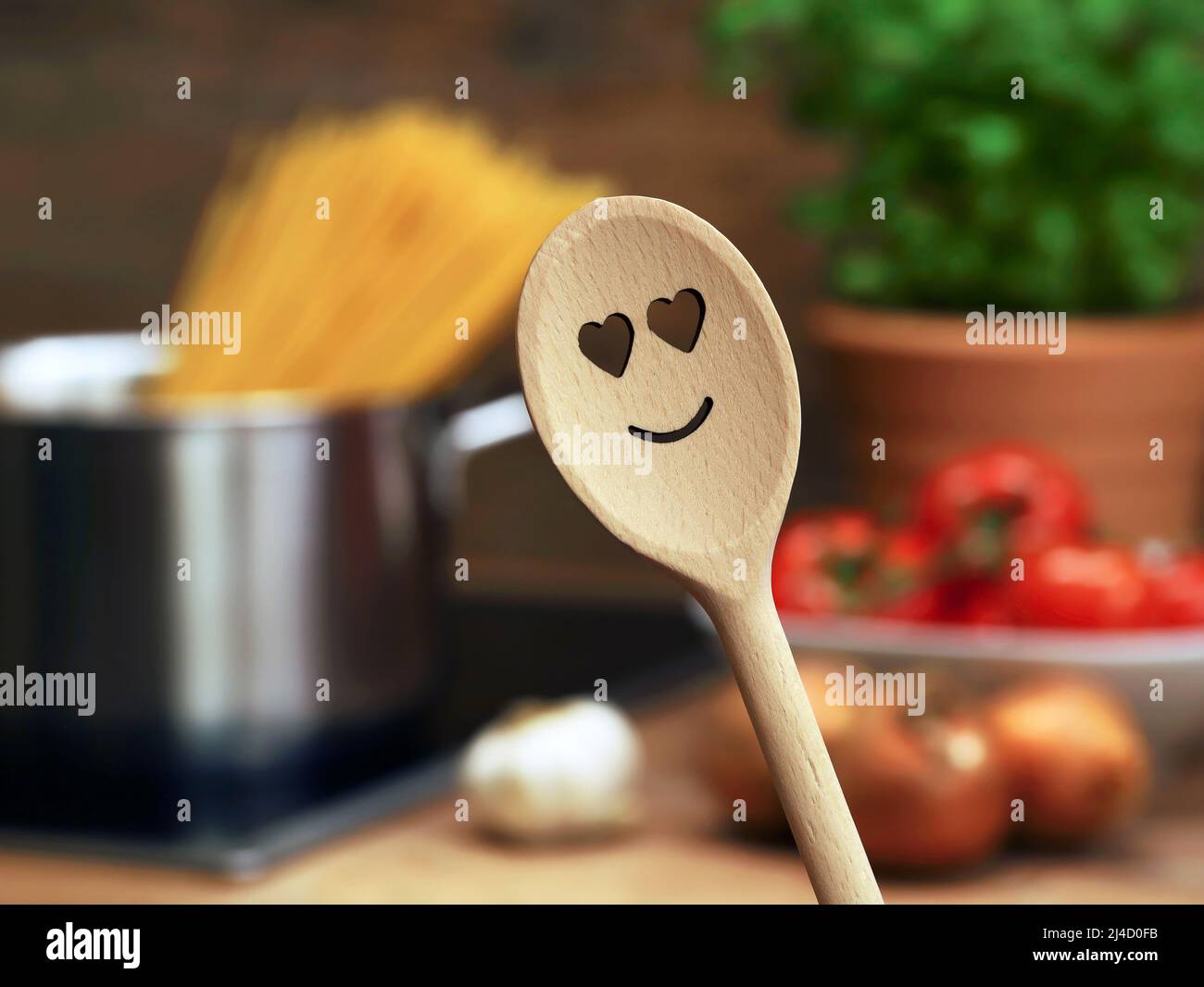 wooden cooking spoon with heart smiley in front of saucepan with ...