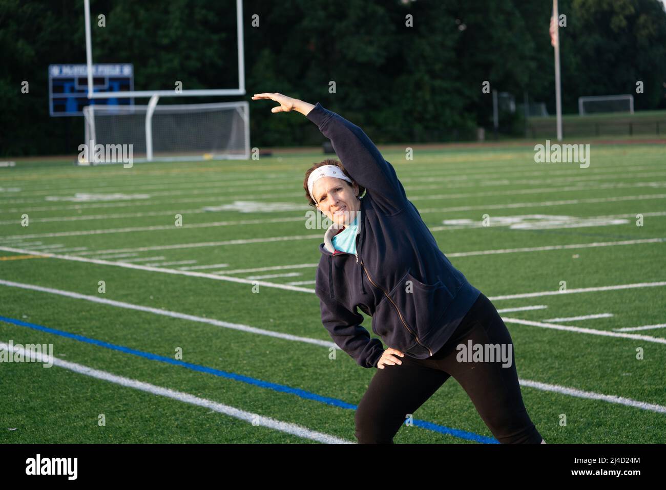 Early morning shot of a middle age woman staying fit by stretching and ...