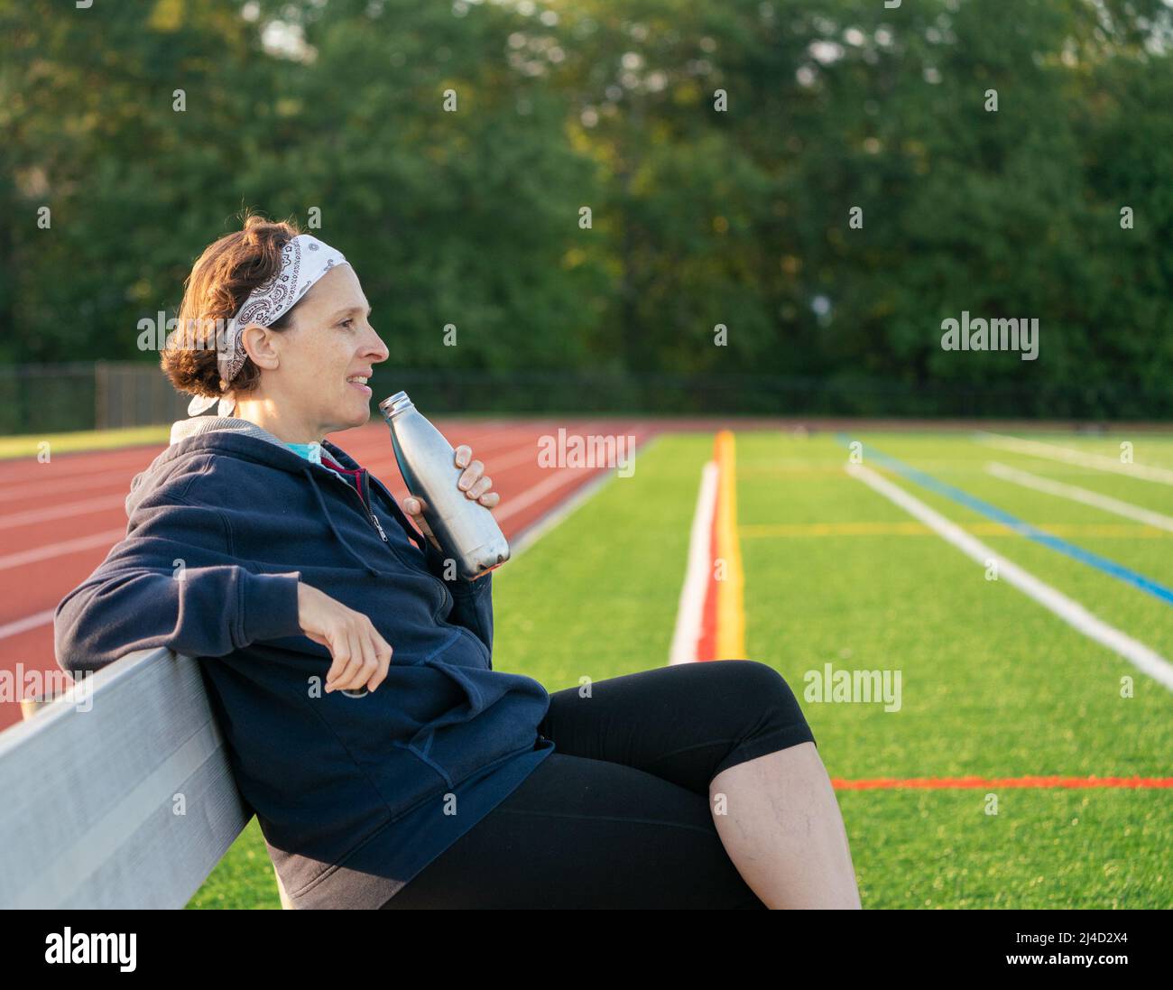 Happy Active middle age woman sitting by a track. Cool down hydration concept Stock Photo - Alamy
