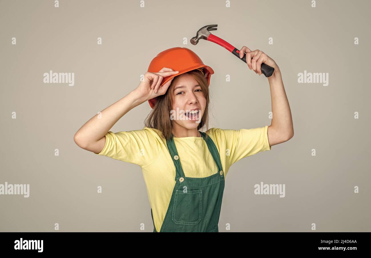 teen girl laborer in protective helmet and uniform on grey background ...