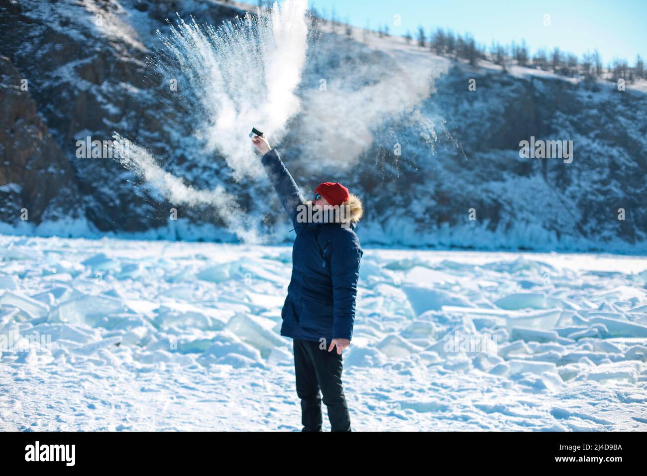 Man in blue jacket pours boiling water from a thermos that turns into a ...
