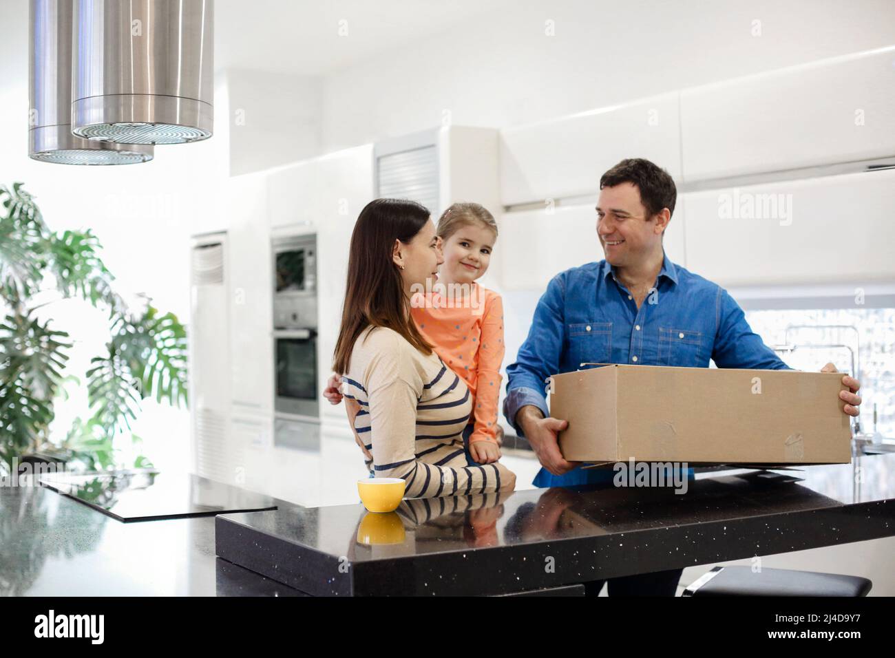 Young happy smiling family three persons unwrapping carton cardboard ...