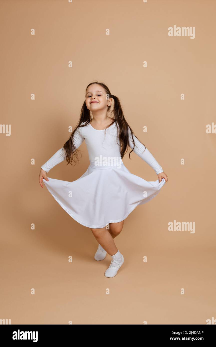 Young happy smiling girl with long dark hair in white dress, socks and ...