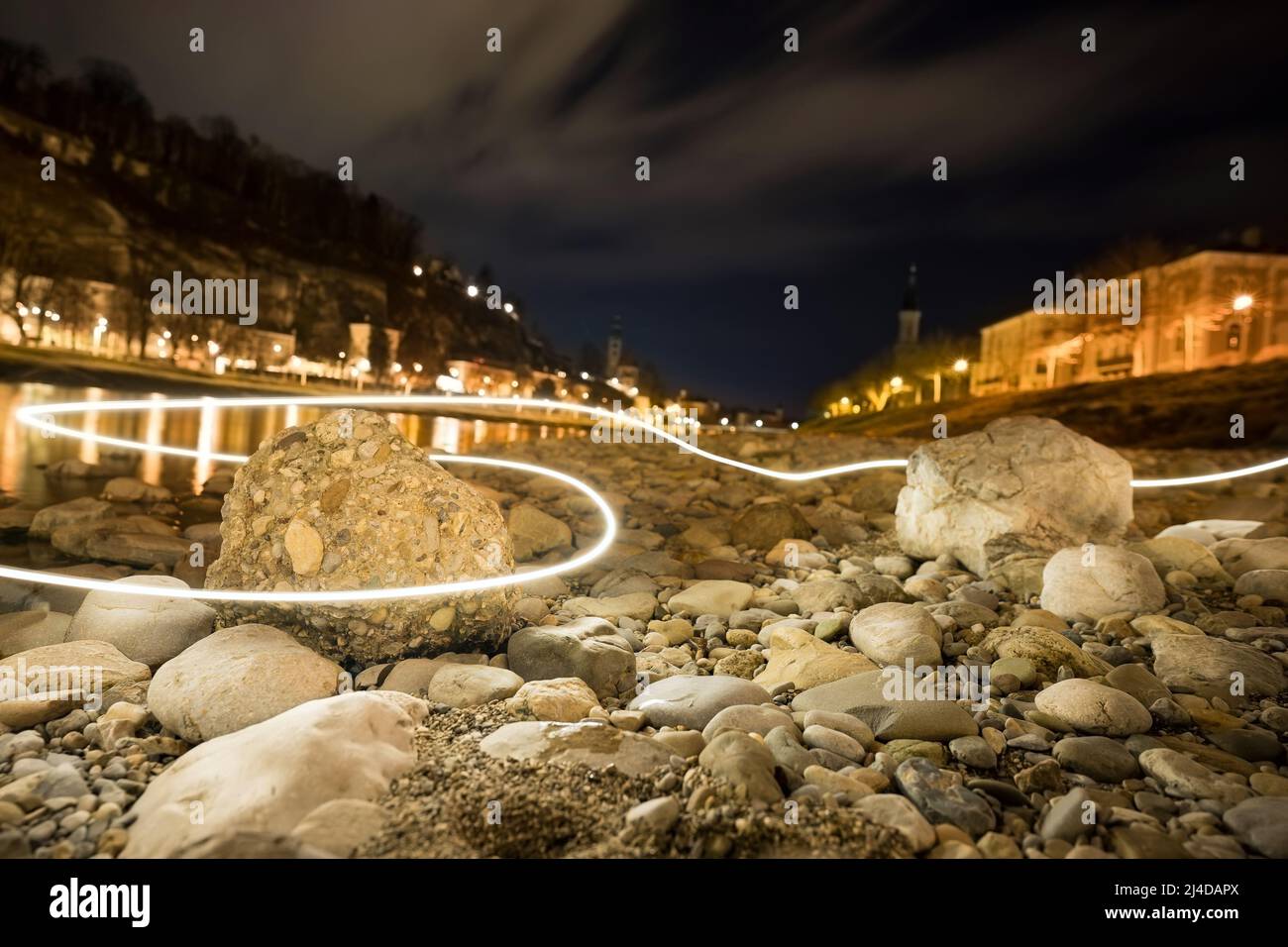 Glowing lights around stones on the river Stock Photo - Alamy