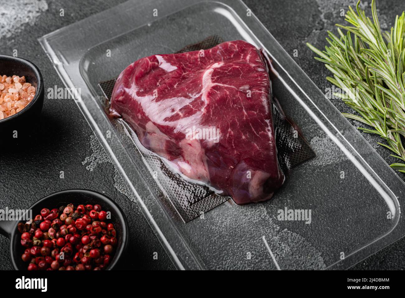 Vacuum black plastic pack with rump beef meat cut, on black dark stone ...