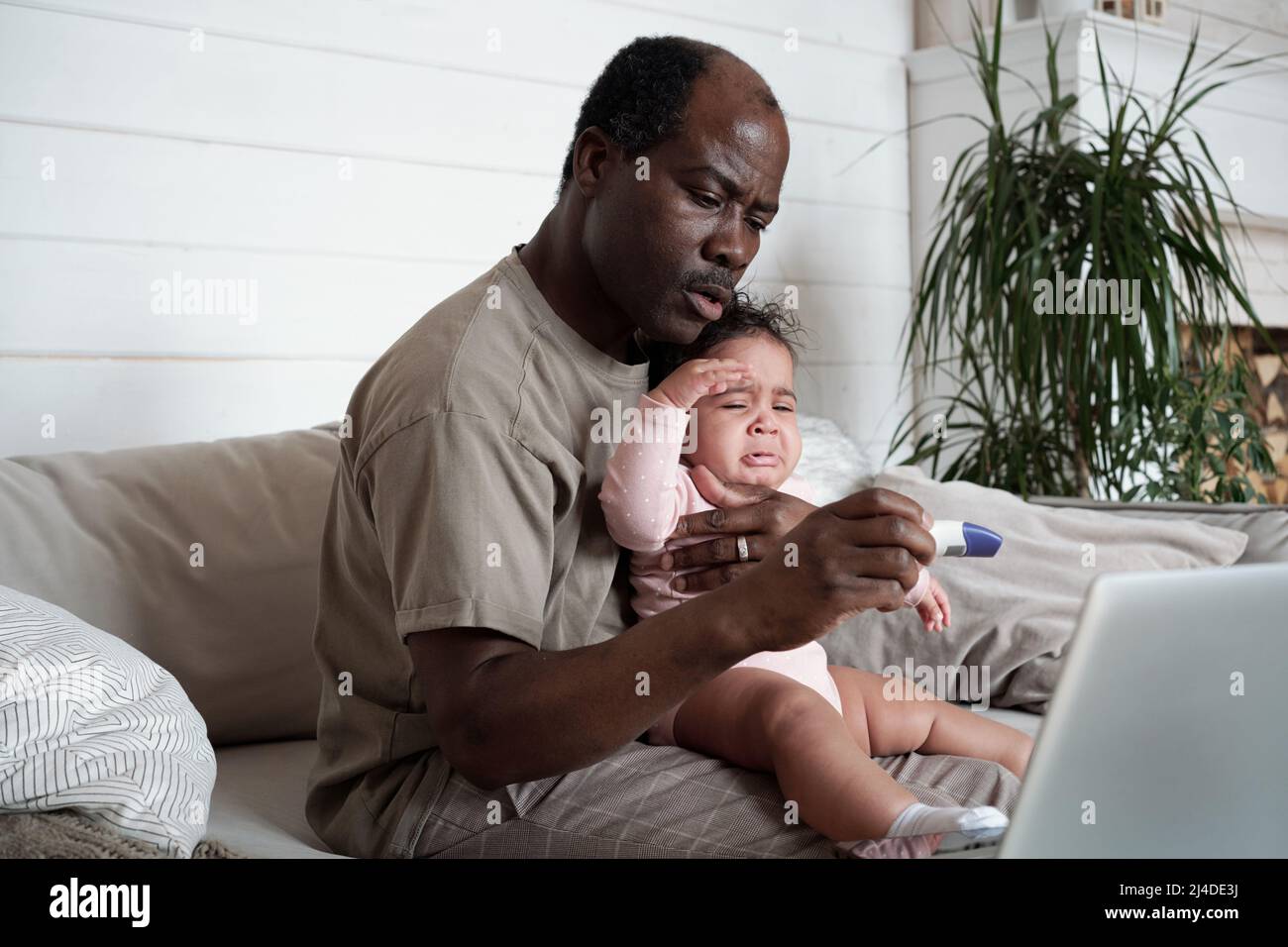 Modern mature African American dad checking body temperature of his ...