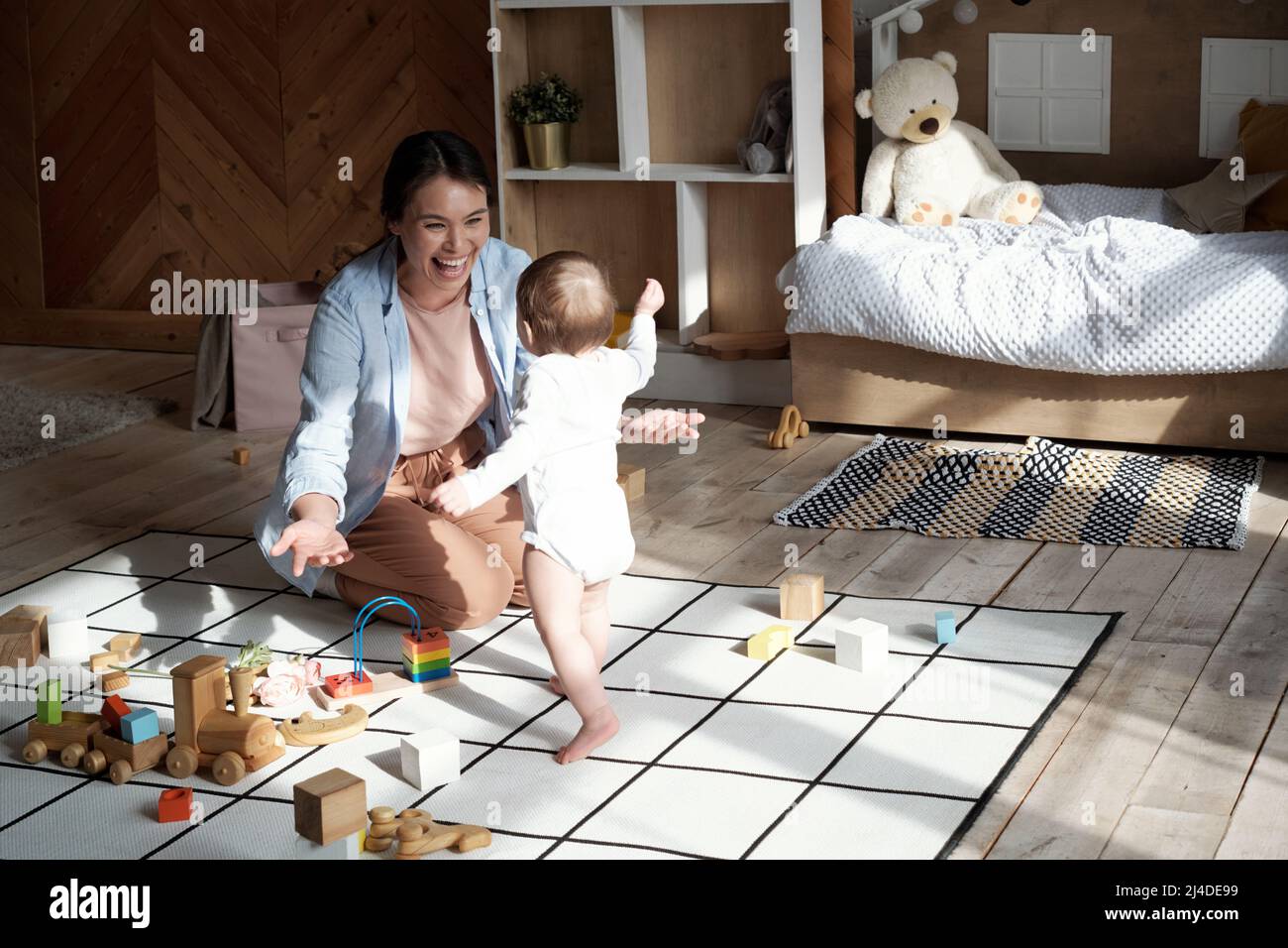Happy young mother sitting on floor in living room going to catch her ...