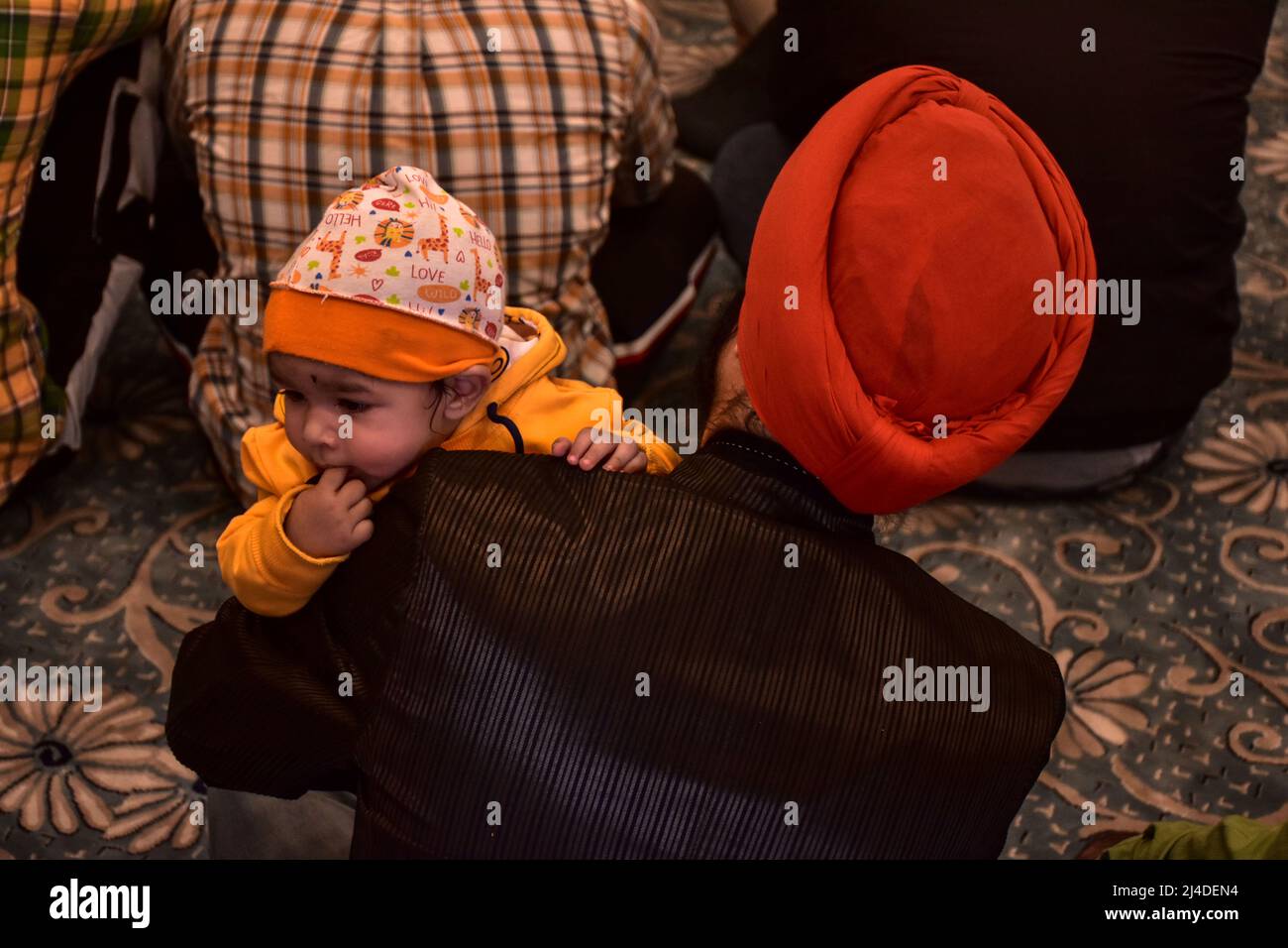 A Sikh devotee holds his baby during rituals inside a Gurdwara or a ...