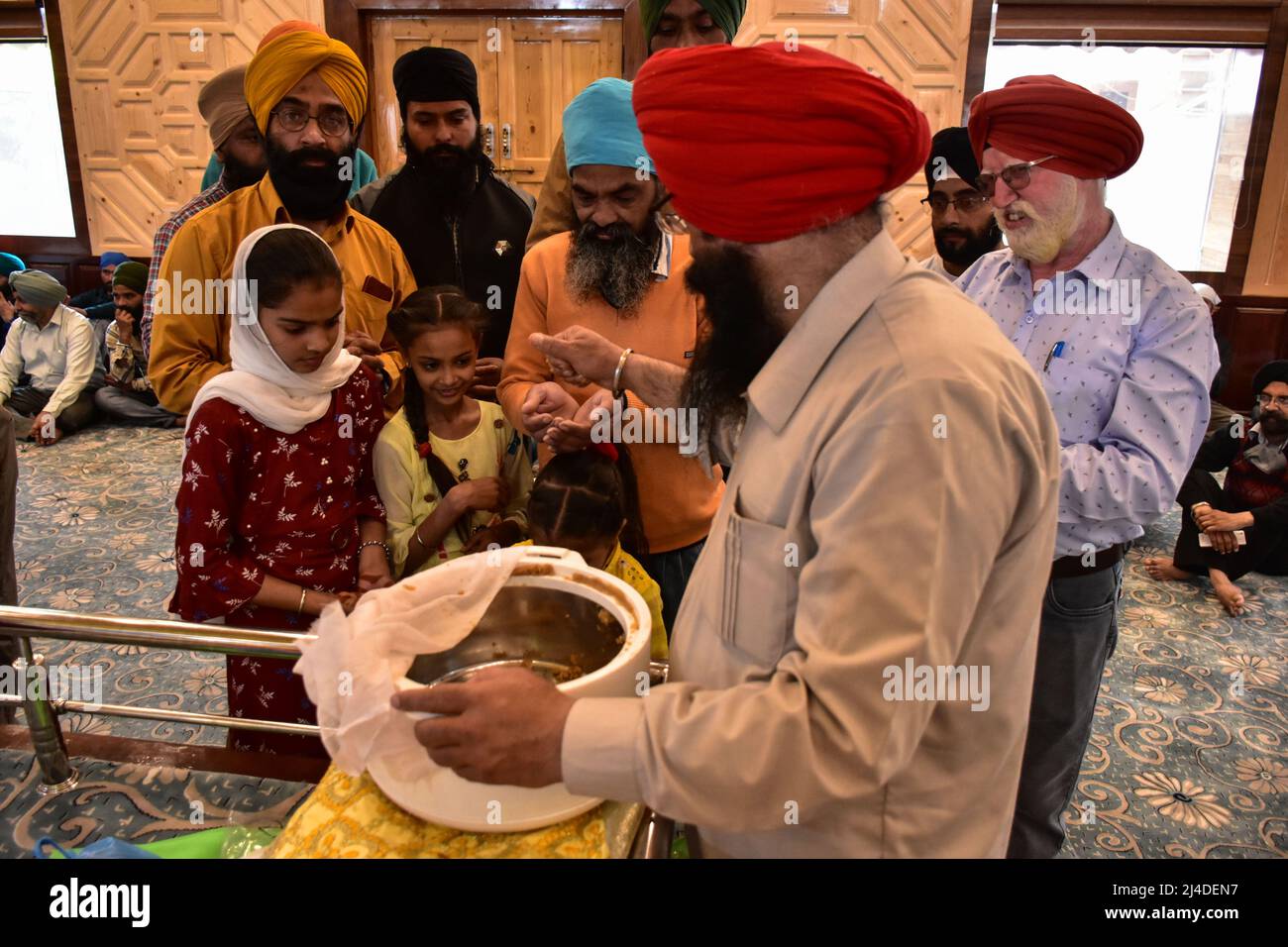 A volunteer provides food among the Sikh devotees inside a Gurdwara or ...