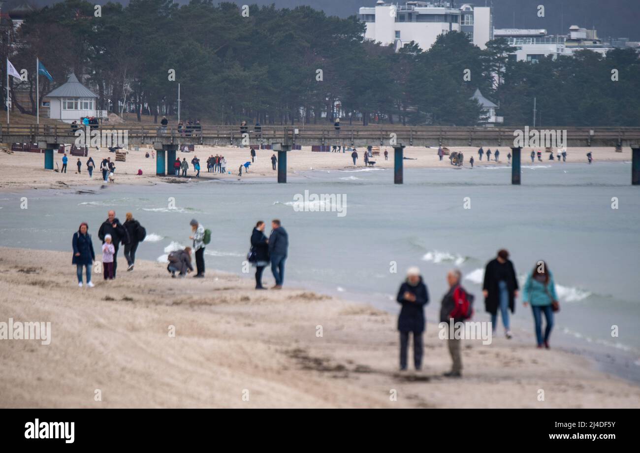 Binz, Germany. 14th Apr, 2022. Tourists walk along the beach in the ...
