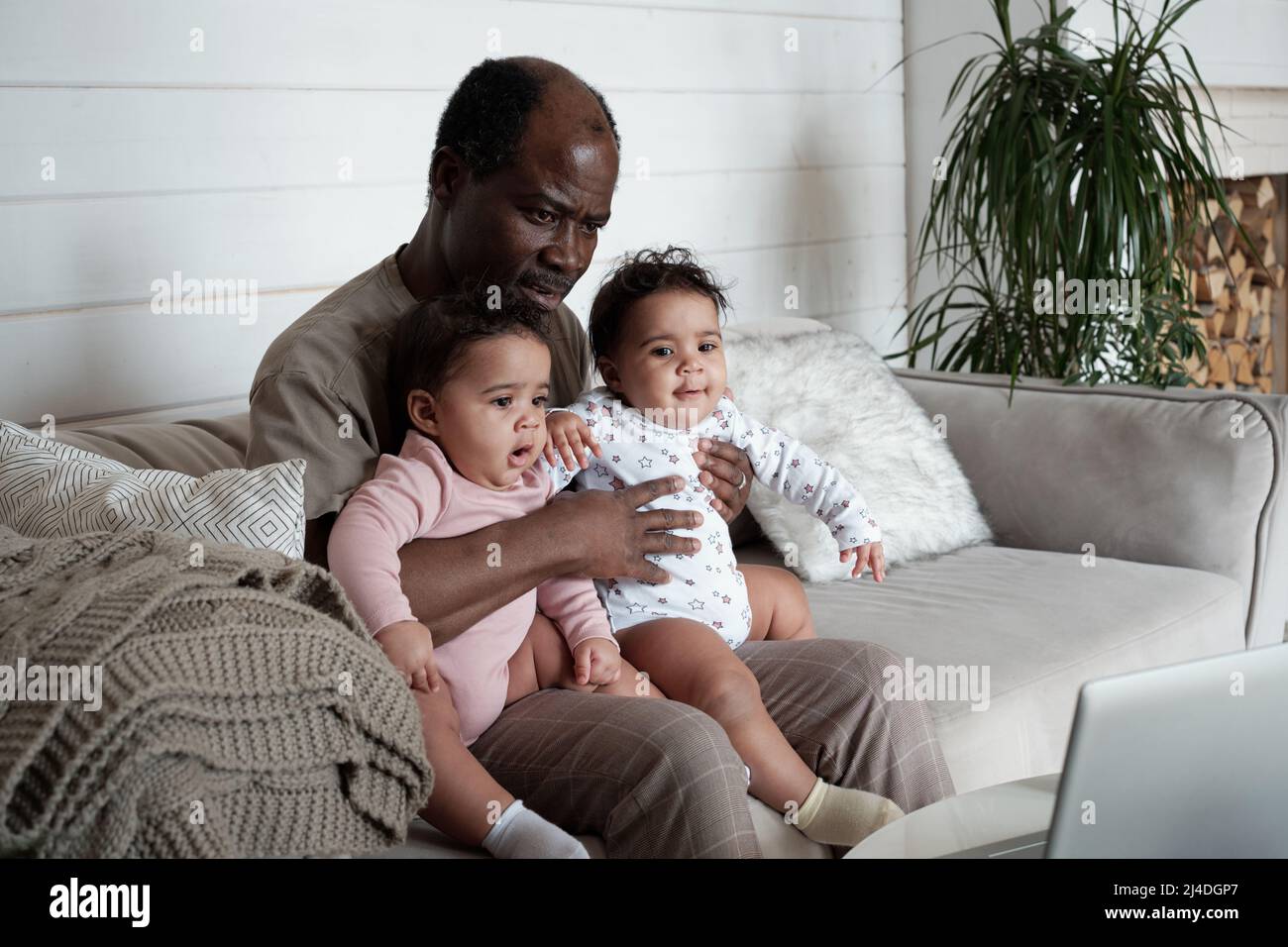 Portrait of mature African American father sitting on sofa in living ...