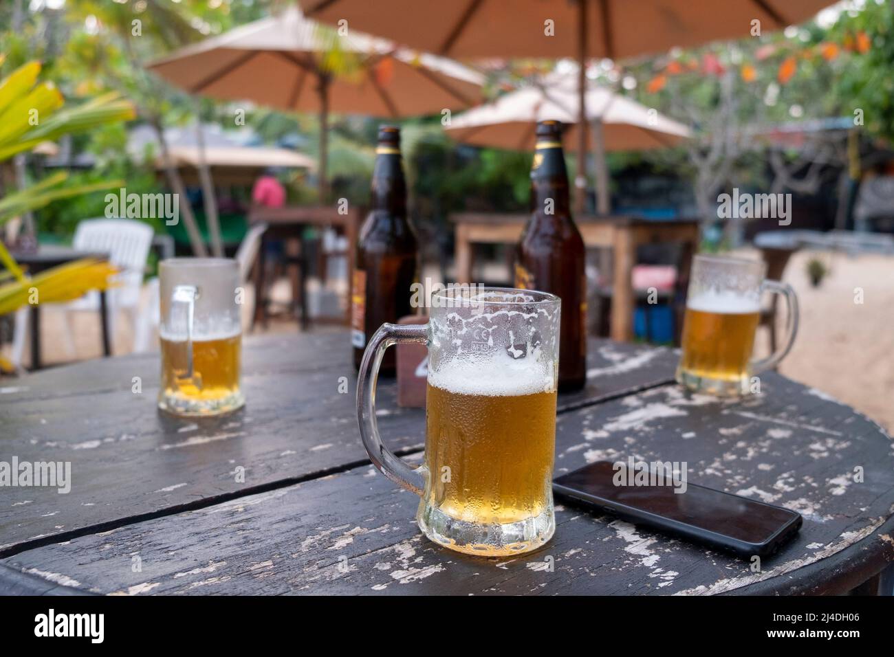 three beers on table and phone at beach Stock Photo - Alamy