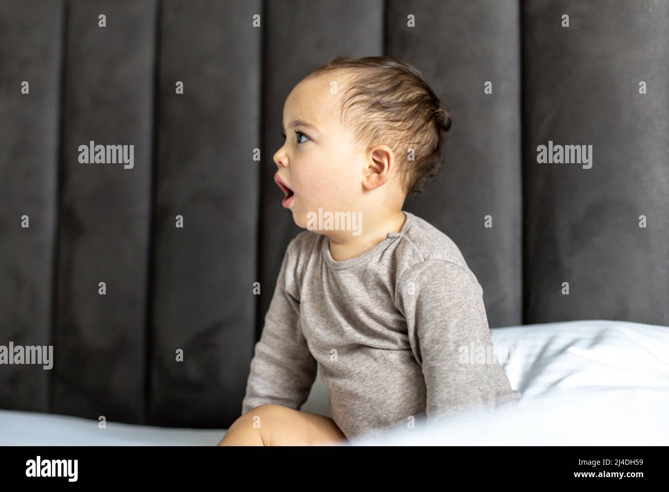 Sweet baby boy on the bed just awake. Funny face of chubby toddler ...