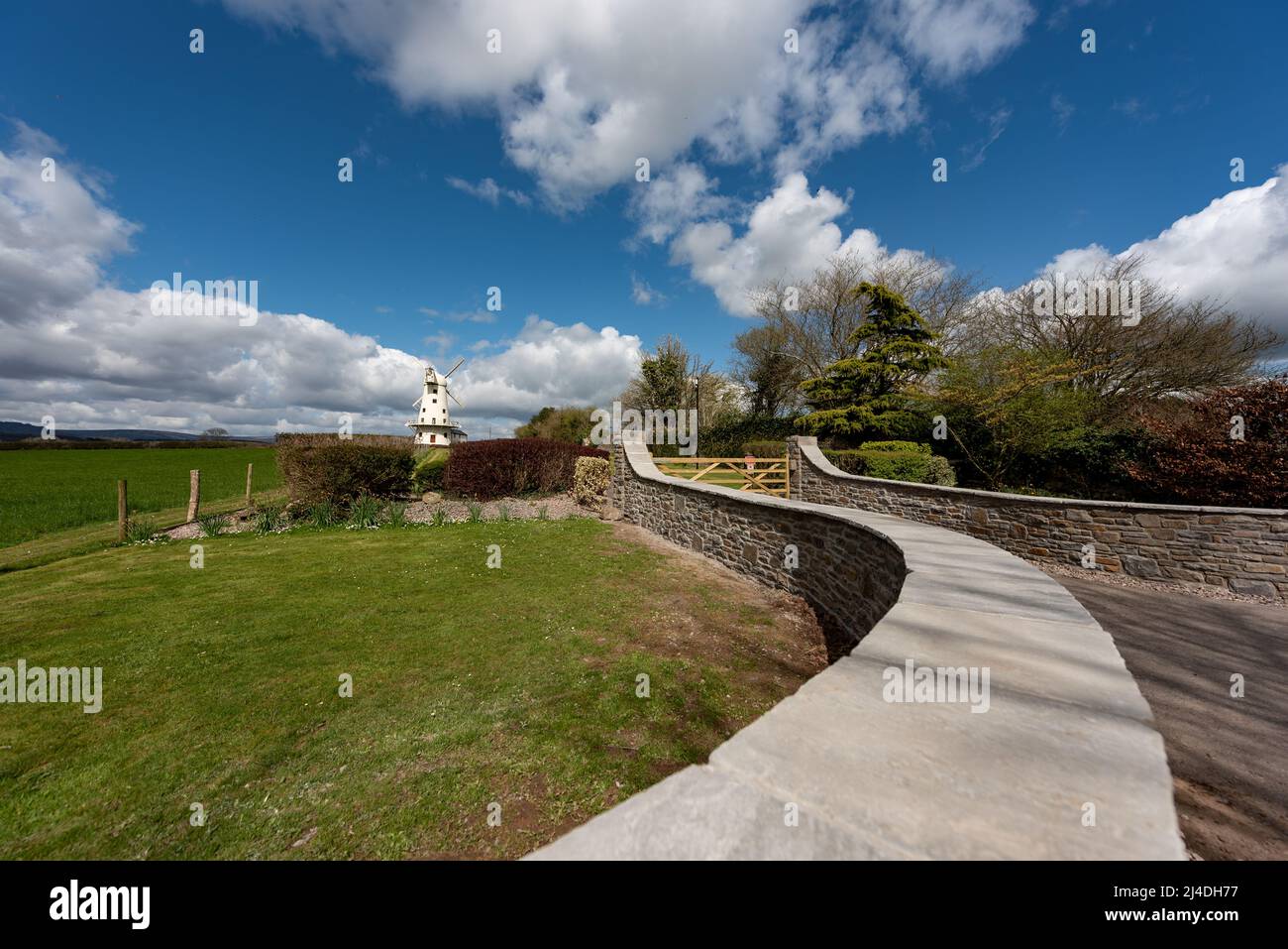 dramatic sky in spring with fluffy clouds leading lines to windmill in ...