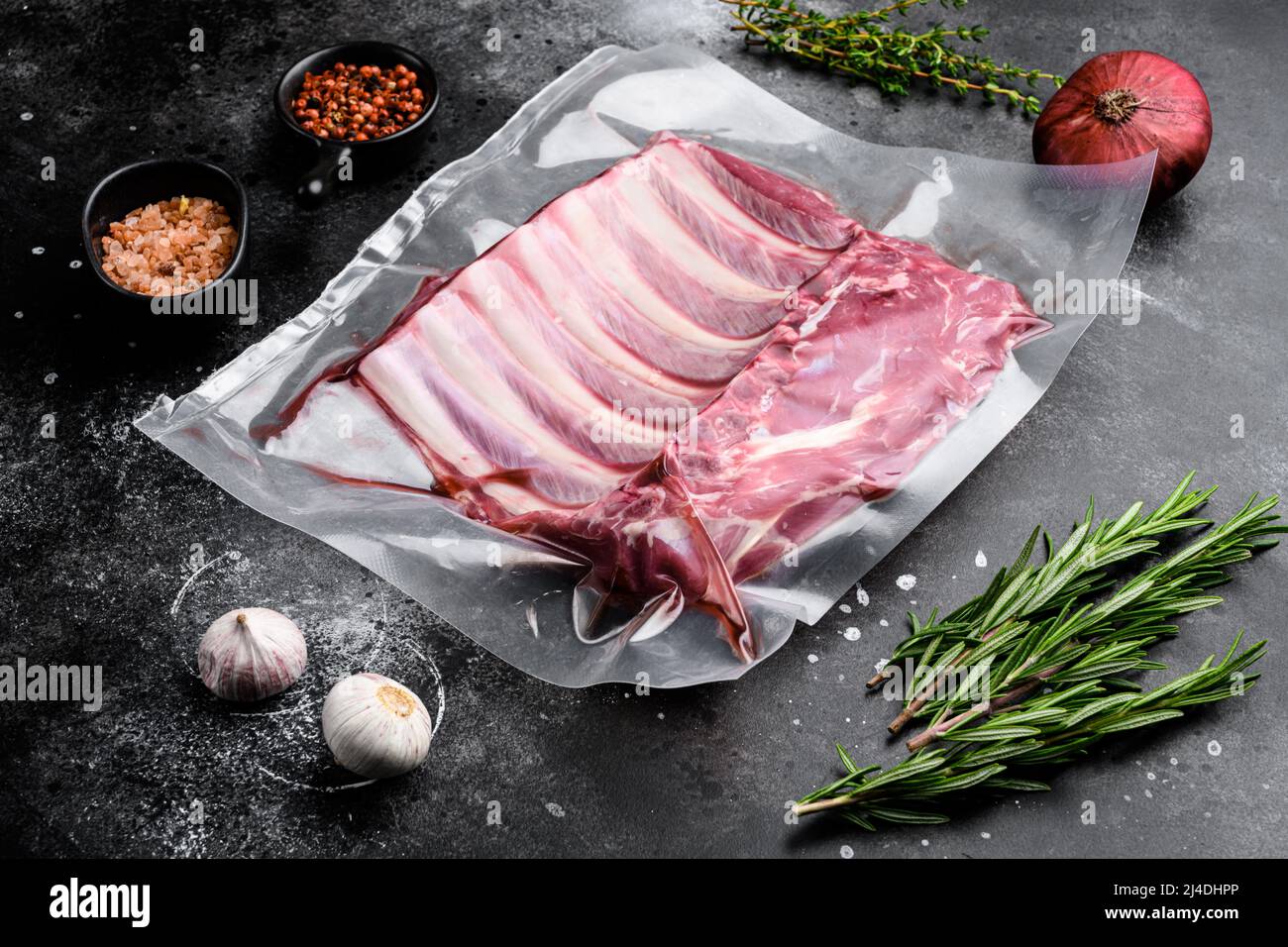 Supermarket packaged raw lamb rib rack set, on black dark stone table ...