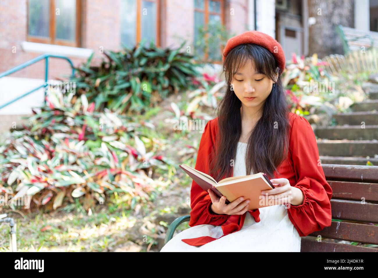 Happy stylish female research student sit on bench read old school ...