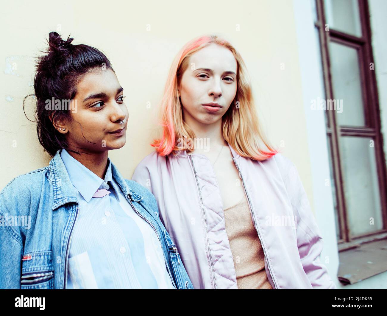 Two teenage girls infront of university building smiling, having fun ...
