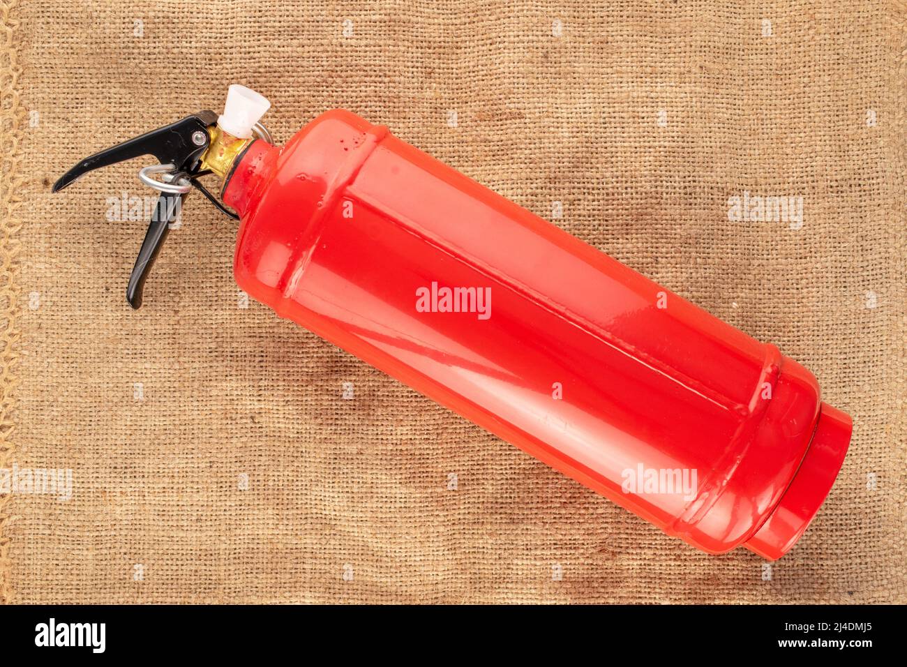 One red fire extinguisher on jute fabric, macro, top view Stock Photo ...