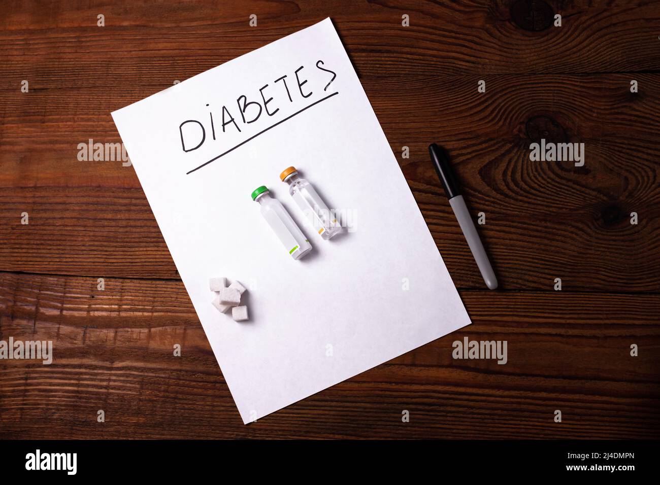 Diabetes sign on a white paper with insulin ampoules, sugar cubes on ...