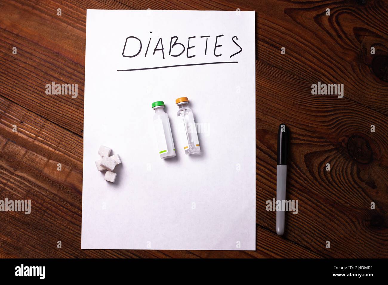 Diabetes sign on a white paper with insulin ampoules, sugar cubes on ...