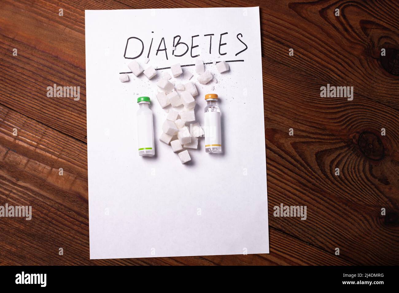 Diabetes sign on a white paper with insulin ampoules, sugar cubes on ...
