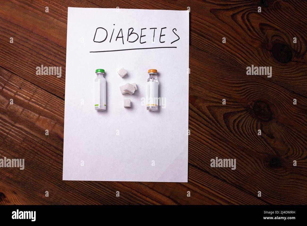 Diabetes sign on a white paper with insulin ampoules, sugar cubes on ...