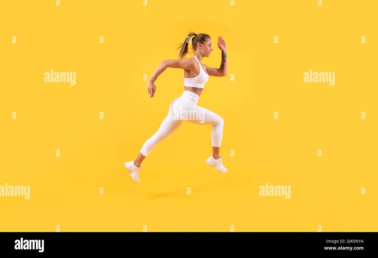 energetic fitness woman runner running on yellow background Stock Photo ...