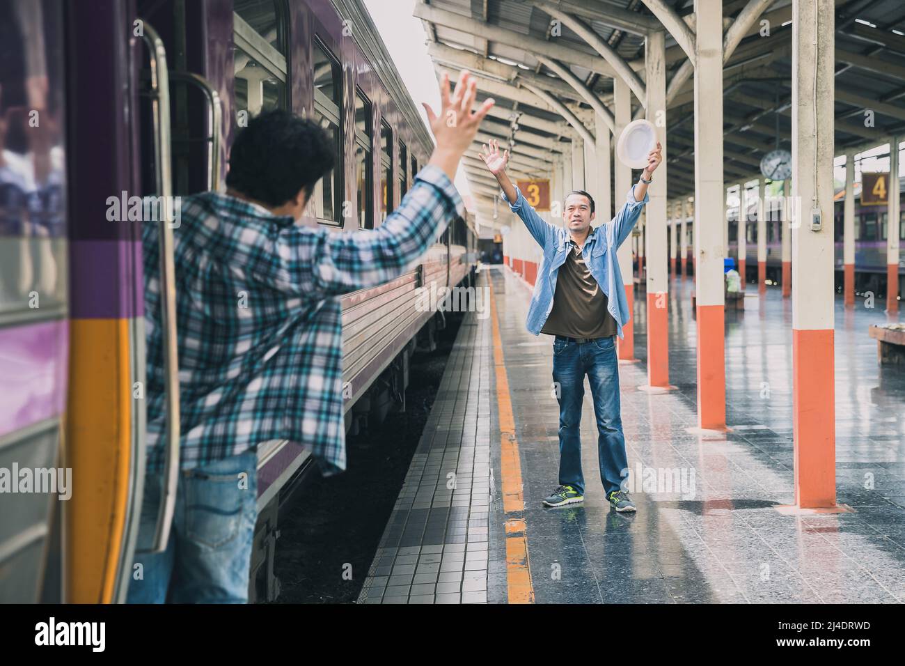 A young man raised hands to greet his friend who was arriving by the ...