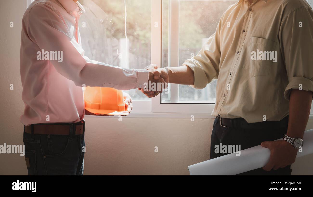 Architect and engineer shaking hands beside the window Stock Photo - Alamy