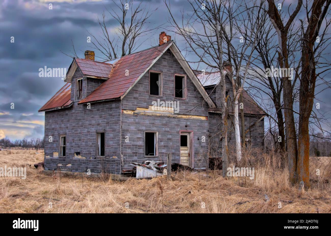 An old abandoned spooky looking farmhouse in winter on a farm yard in ...
