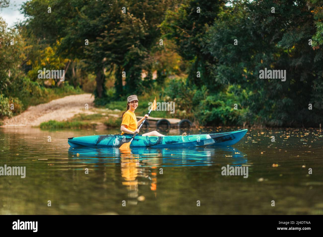 World Tourism Day. Happy smiling girl floating in blue kayak at river ...