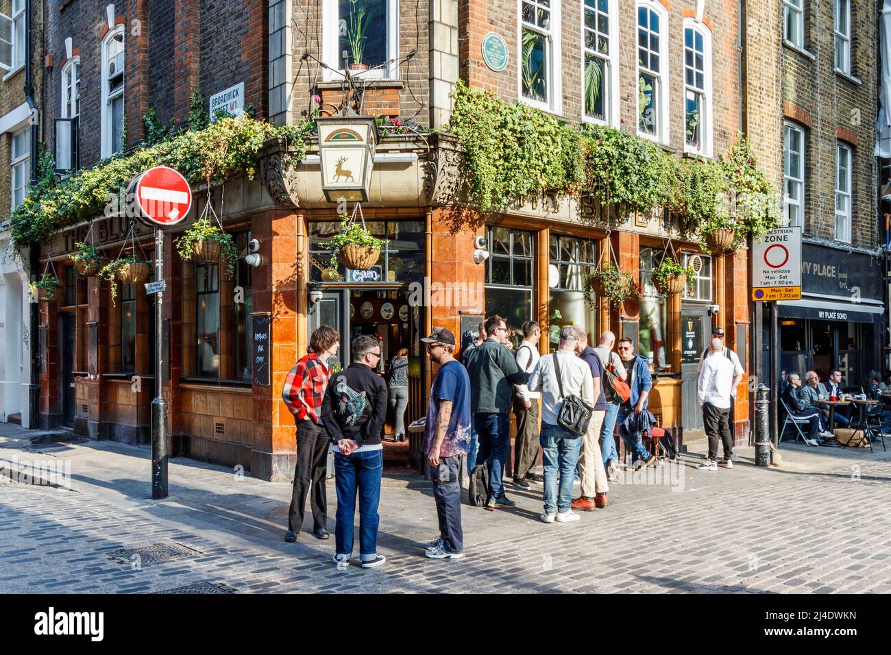 Customers drinking outside the Blue Post pub in Soho as warmer weather ...