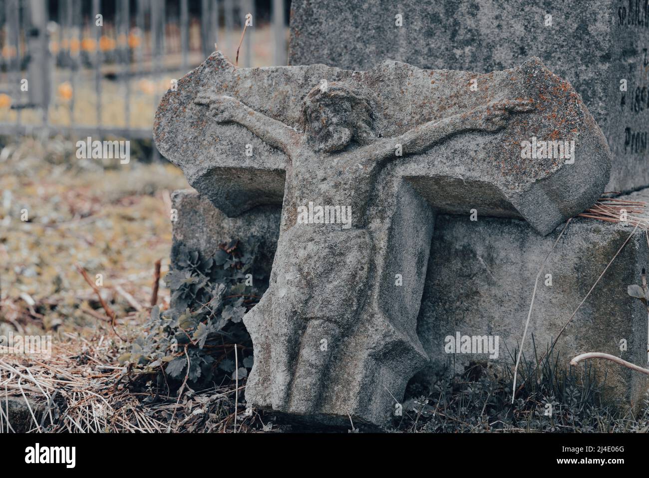 Toppled stone crucifix, broken gravestone at abandoned ancient cemetery ...
