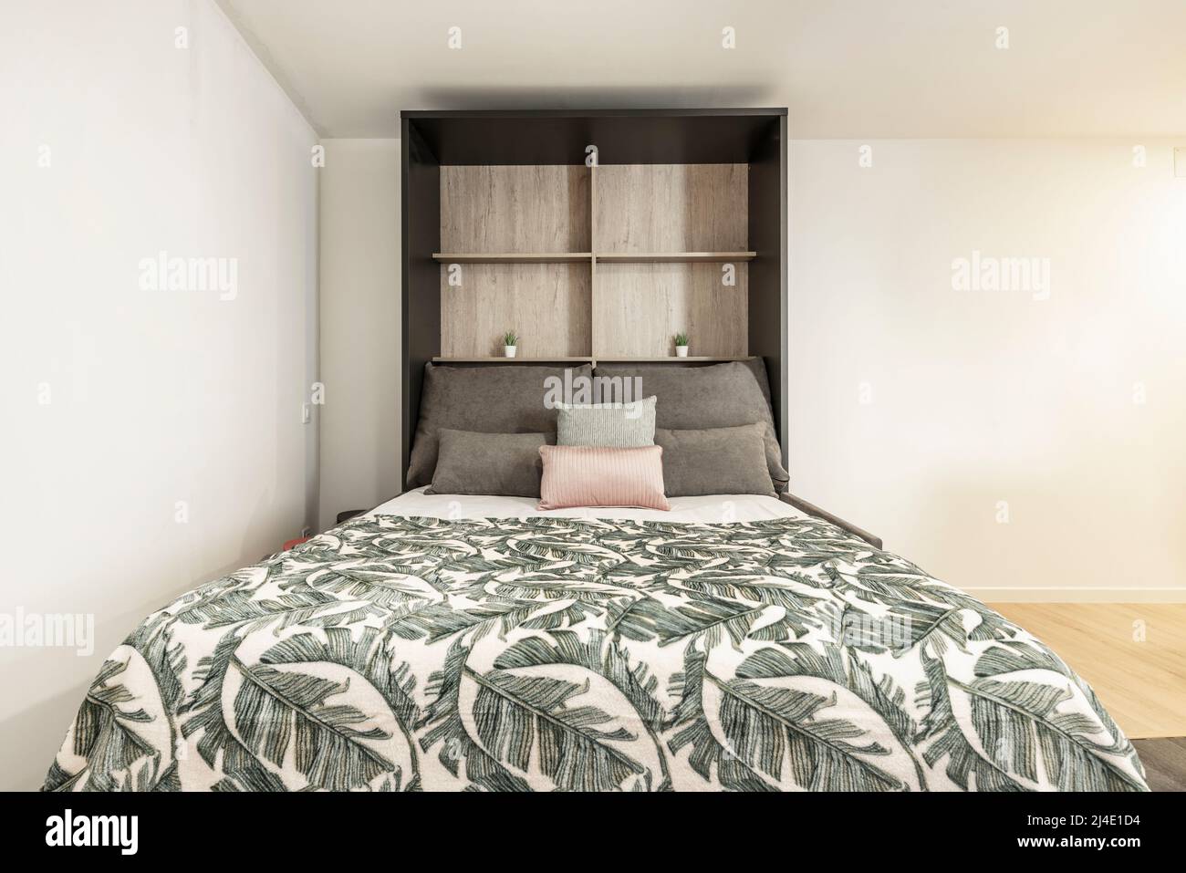 Extended pull-out bed with cushions, plant-print blankets and white ...