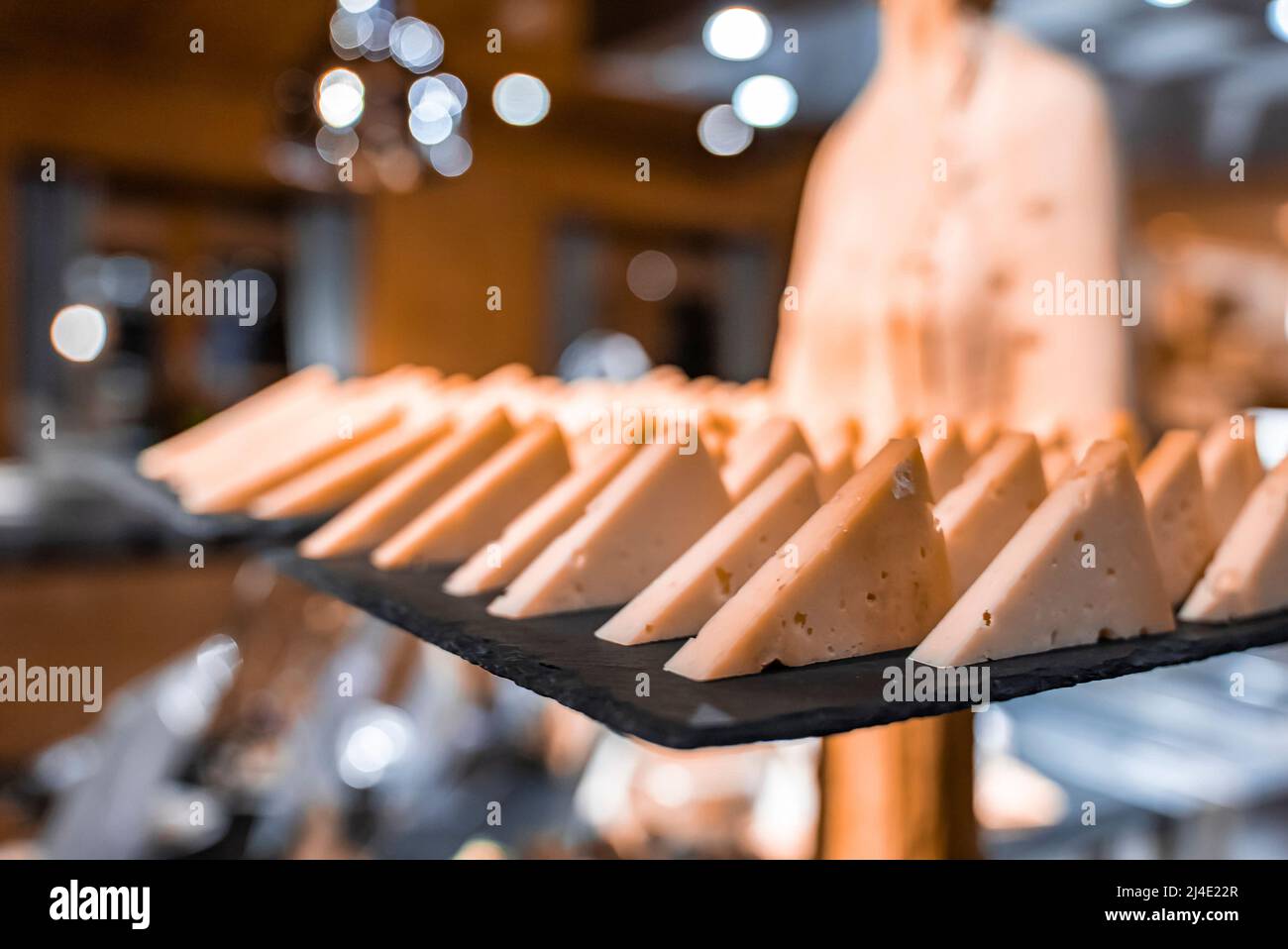 Cheese in triangle shape slices displayed in tray on counter at resort ...