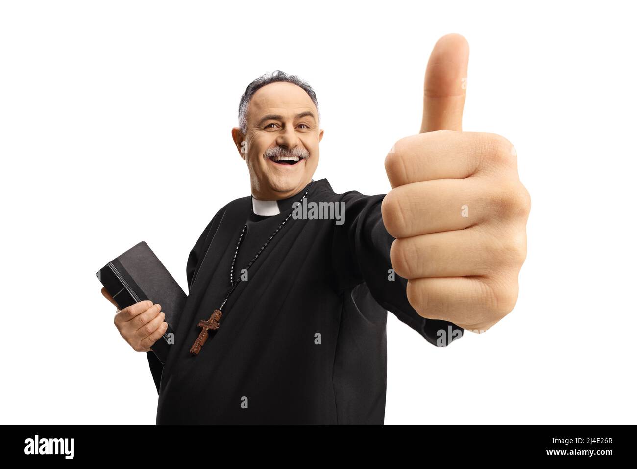 Cheerful catholic priest gesturing thumbs up and holding a bible ...